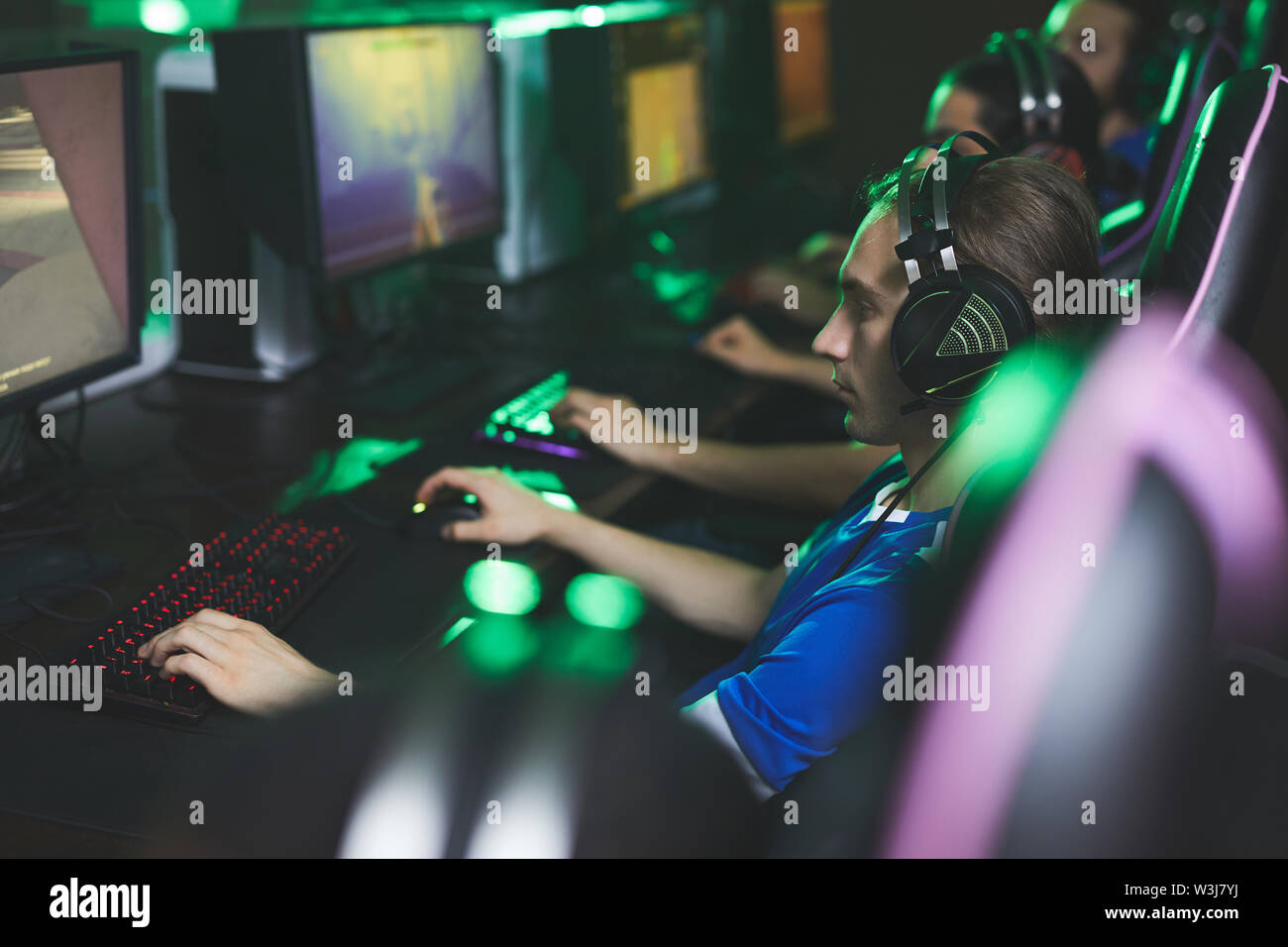 Group of serious young men in headsets sitting in line and using ...