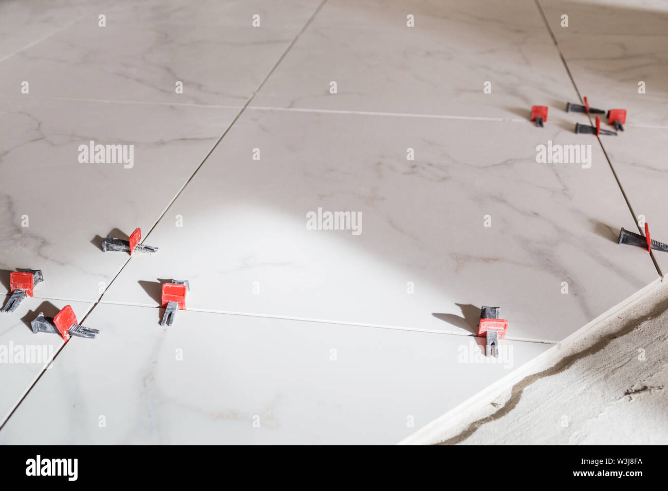 Tile leveling system with plastic clips and wedges Stock Photo - Alamy