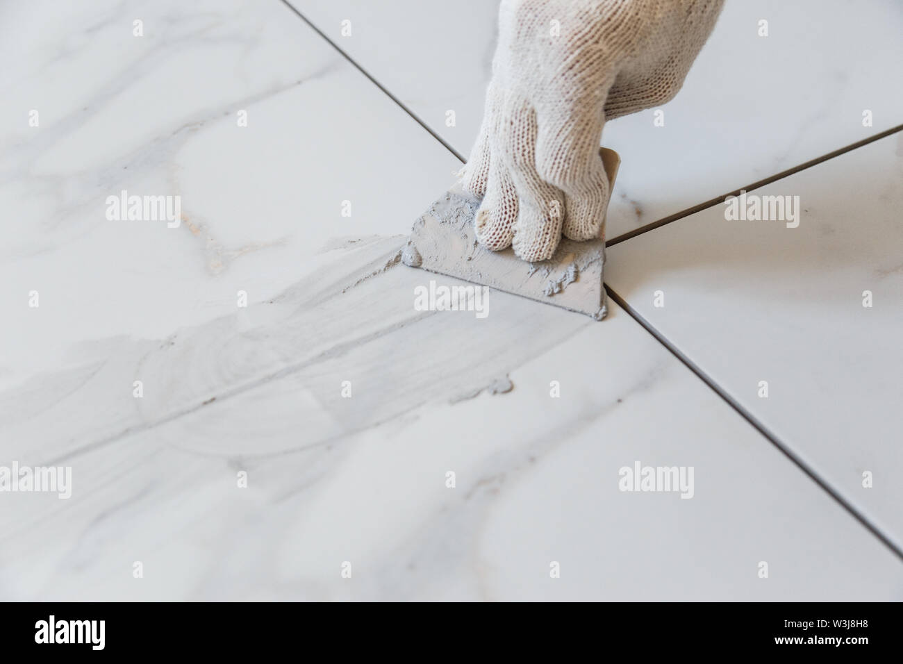 Grouting tiles seams with a rubber trowel Stock Photo - Alamy