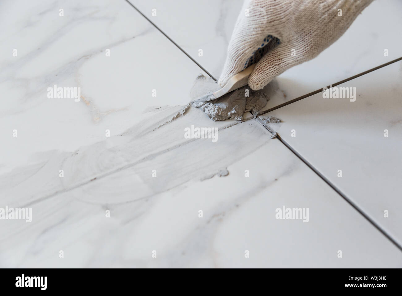 Grouting tiles seams with a rubber trowel Stock Photo - Alamy