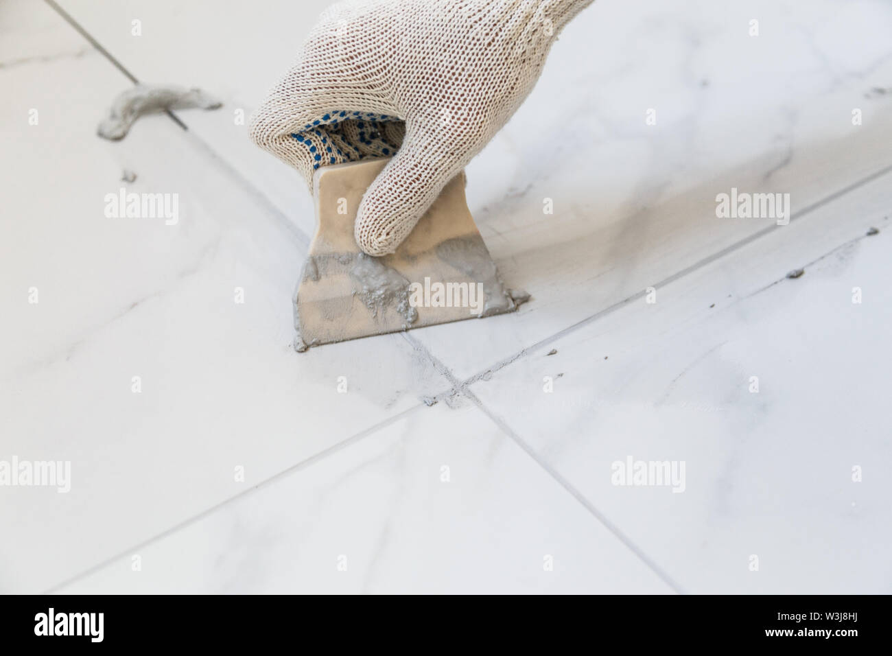Grouting tiles seams with a rubber trowel Stock Photo - Alamy