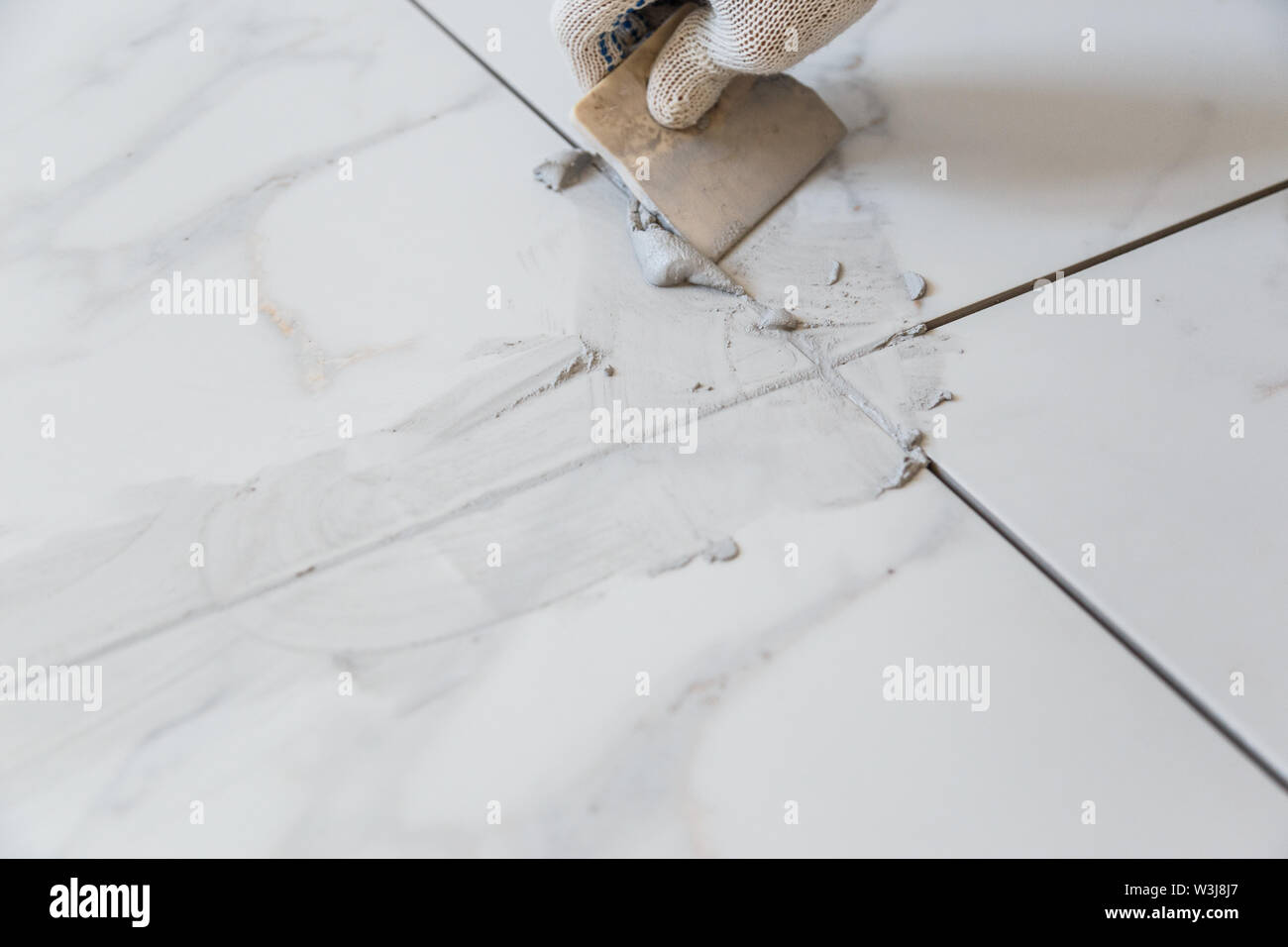 Grouting tiles seams with a rubber trowel Stock Photo - Alamy