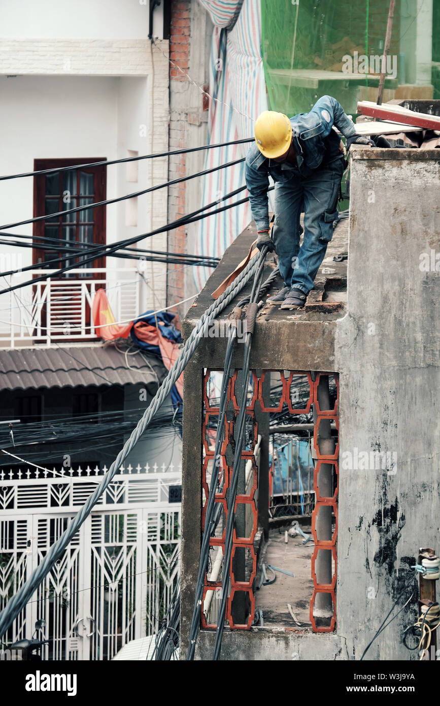 Vietnamese electricity worker climb high on house roof repair ...