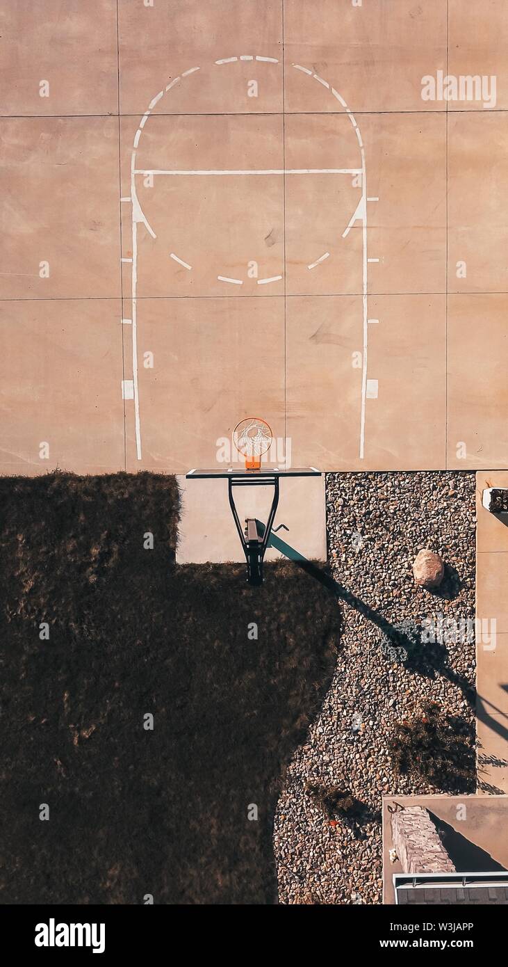 Overhead shot of a cement basketball field with the hoop and rocks ...