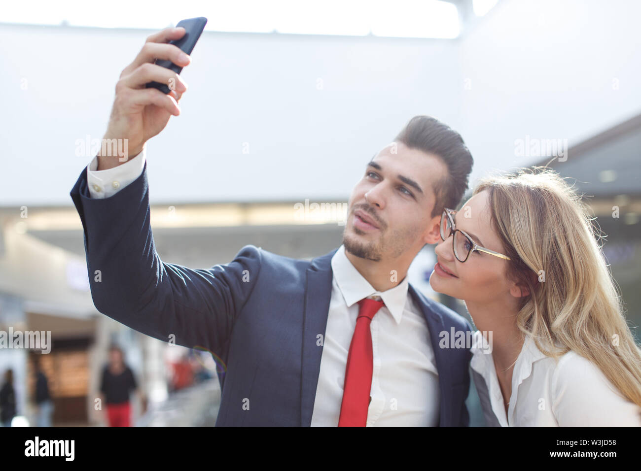 Young businesspeople taking selfie, or video call in business center ...