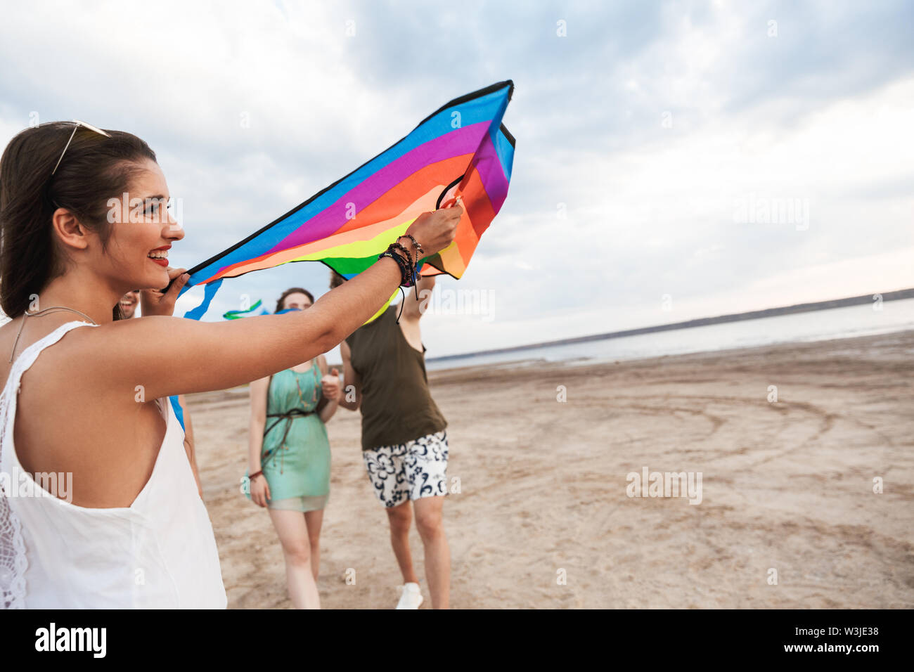 Group of a cheerful young friends having fun at the beach, playing with ...