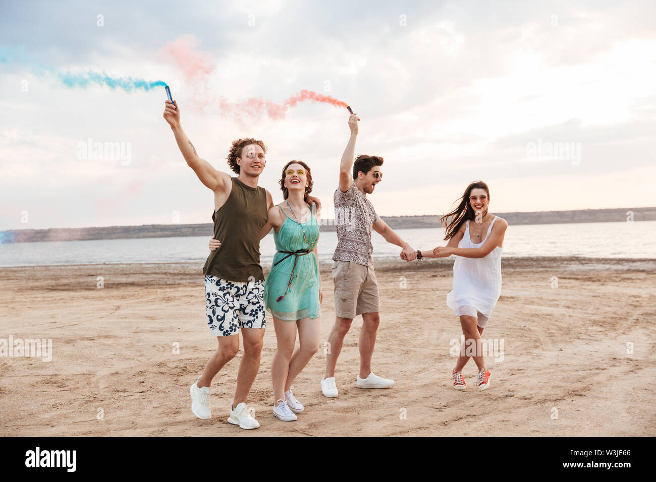 Group of a cheerful young friends having fun at the beach, holding ...