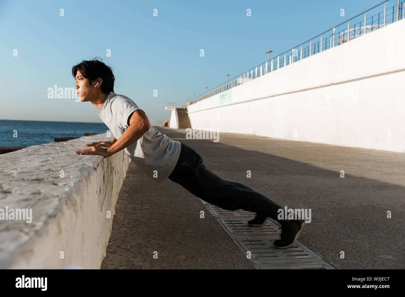 Confident fit asian sportsman doing push-ups at the seashore Stock ...