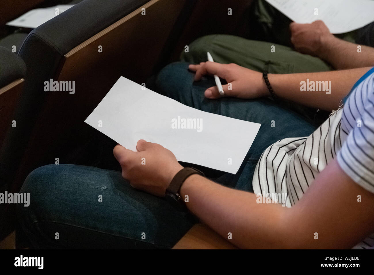 Close up of man holding paper sheet and pen while waiting exam ...