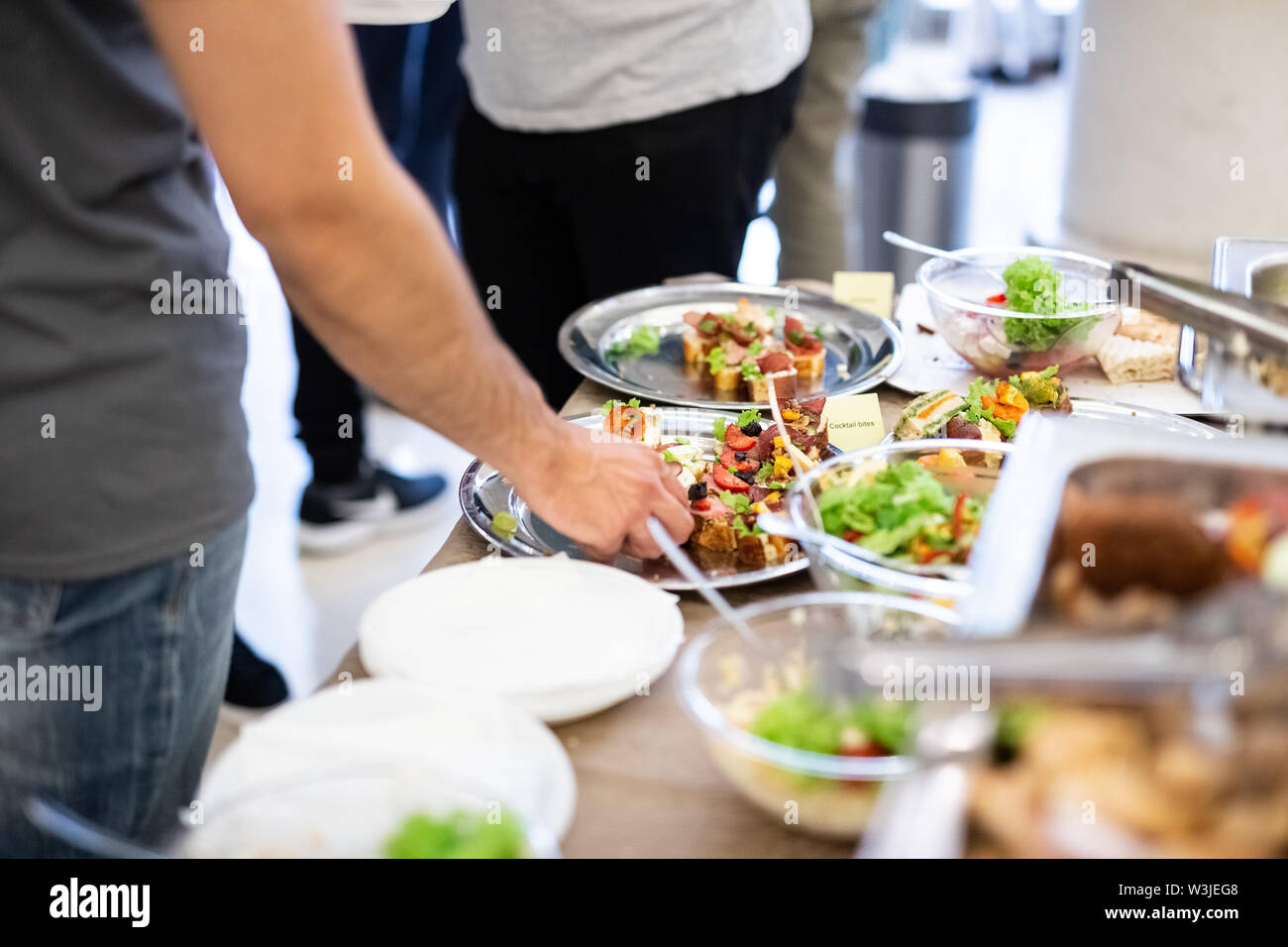 Buffet table with food and self service people picking up from plate at ...