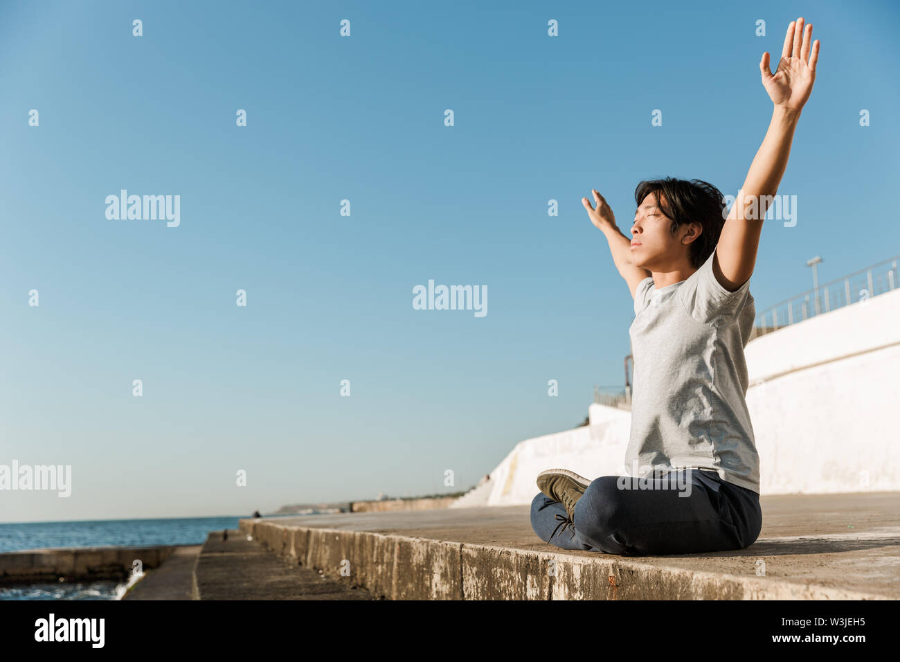 Calm healthy asian man doing yoga exercises at the beach, meditating ...