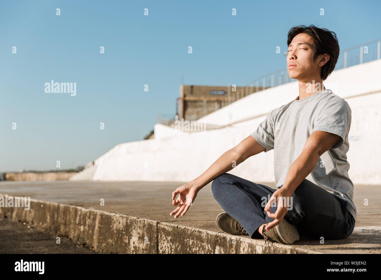 Calm healthy asian man doing yoga exercises at the beach, meditating ...