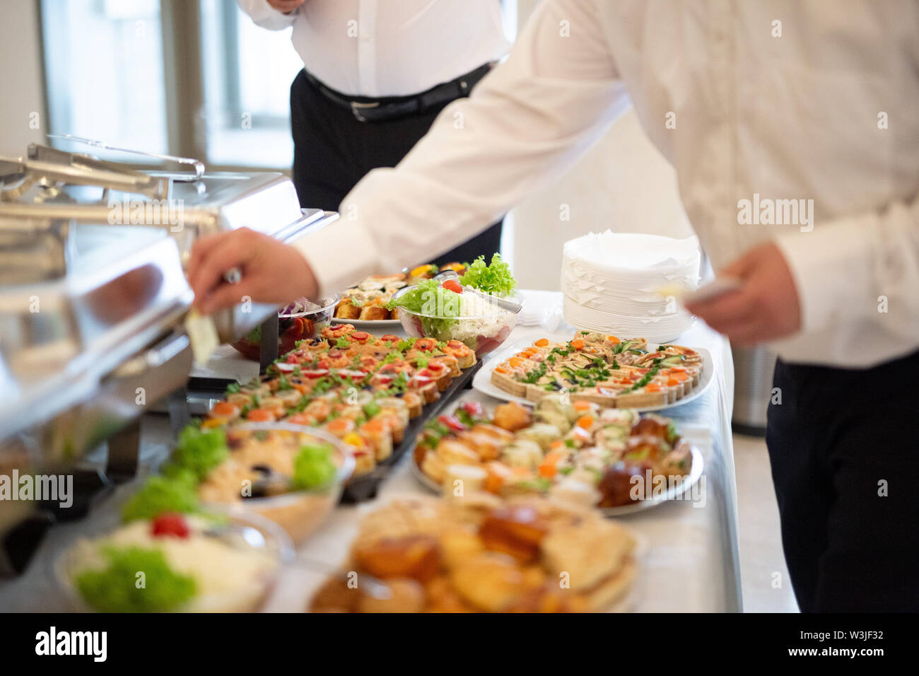 Waiters preparing buffet canape food table Stock Photo - Alamy
