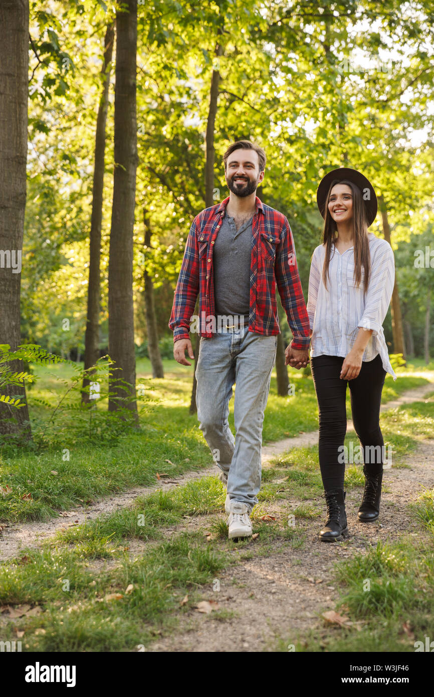 Image of a cheerful positive young loving couple walking outdoors in a ...