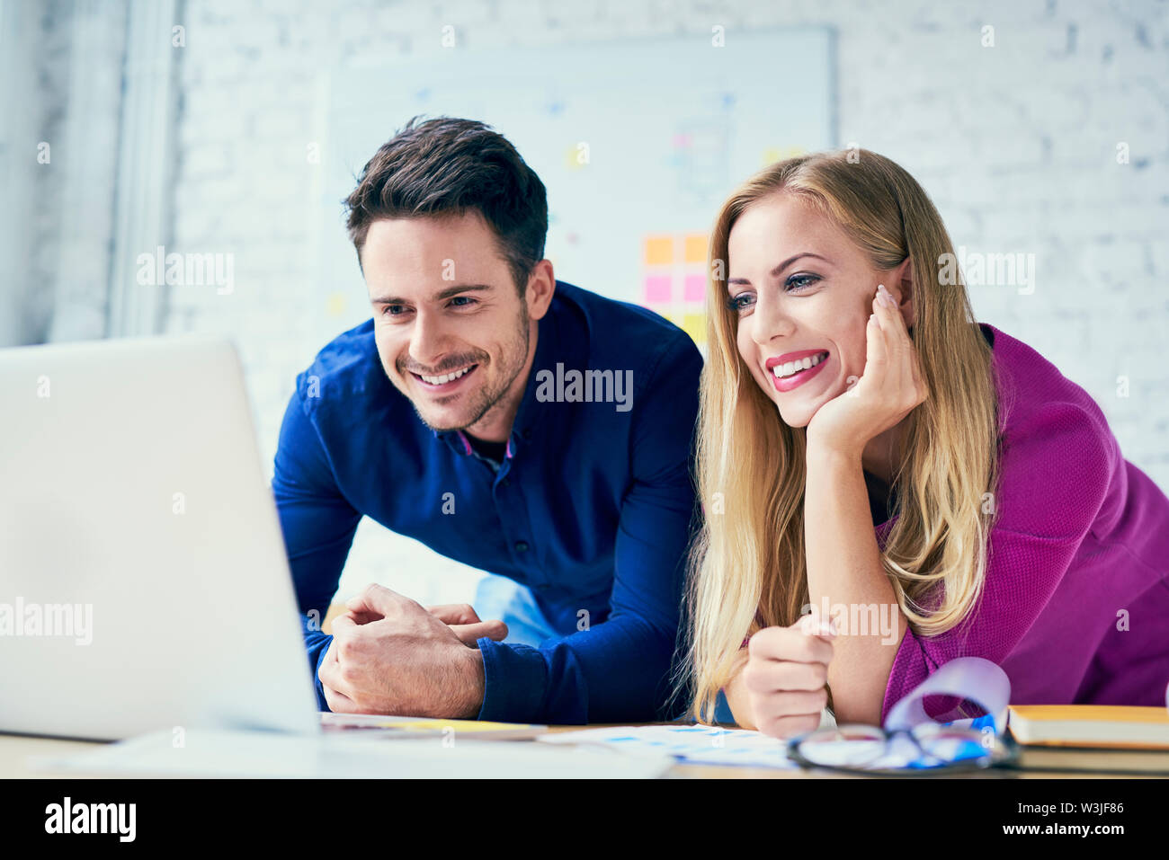 Happy two people collaborationg in office, working together on laptop ...