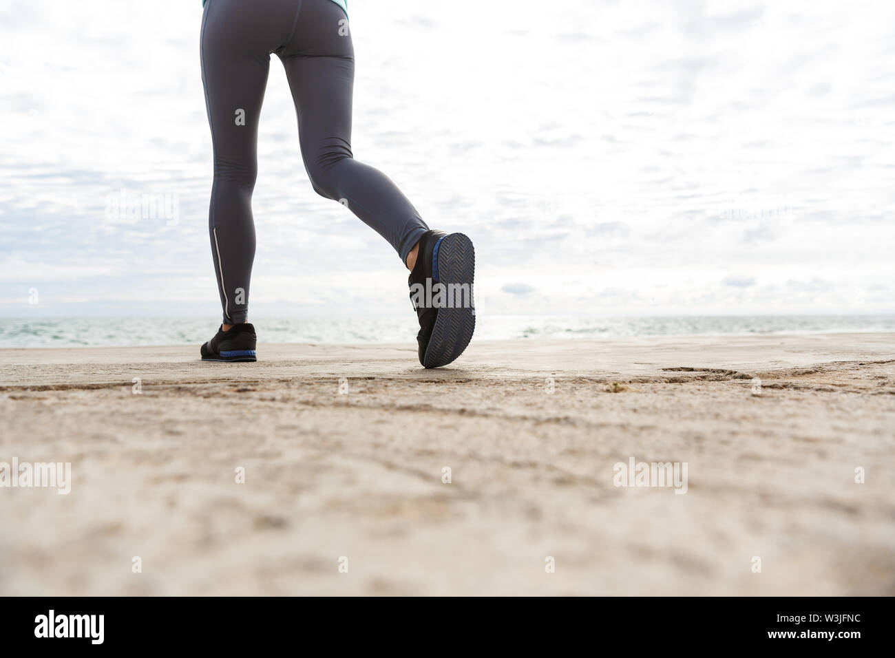 Close up back view of sportswomen's legs running at the beach Stock ...