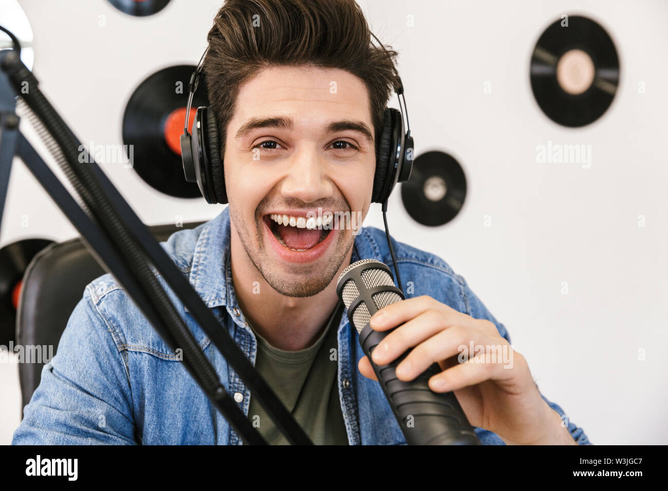 Happy young man radio host broadcasting through microphone in studio ...