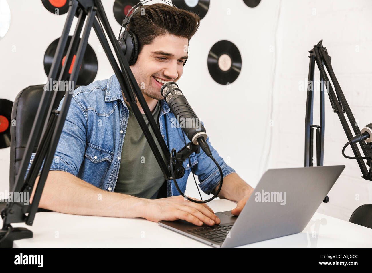 Handsome happy young male radio host broadcasting in studio, using ...