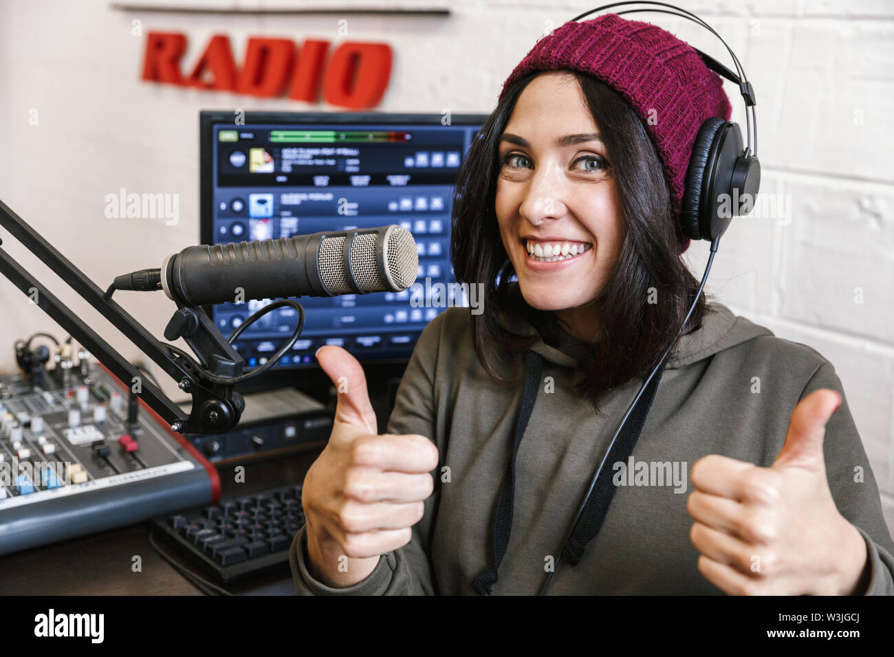 Cheerful young woman radio host broadcasting through microphone in ...