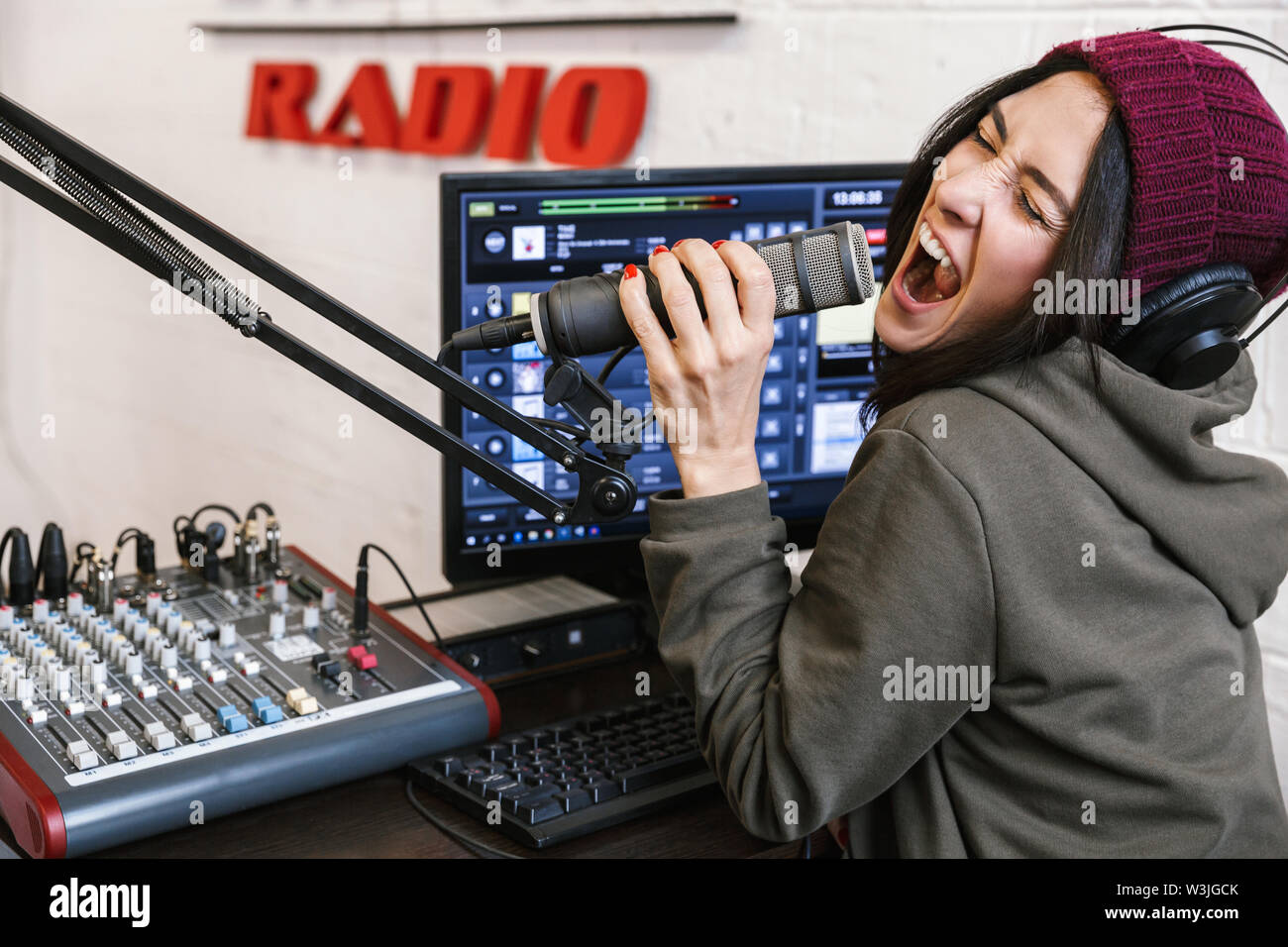 Beautiful happy young female radio host broadcasting in studio, using ...