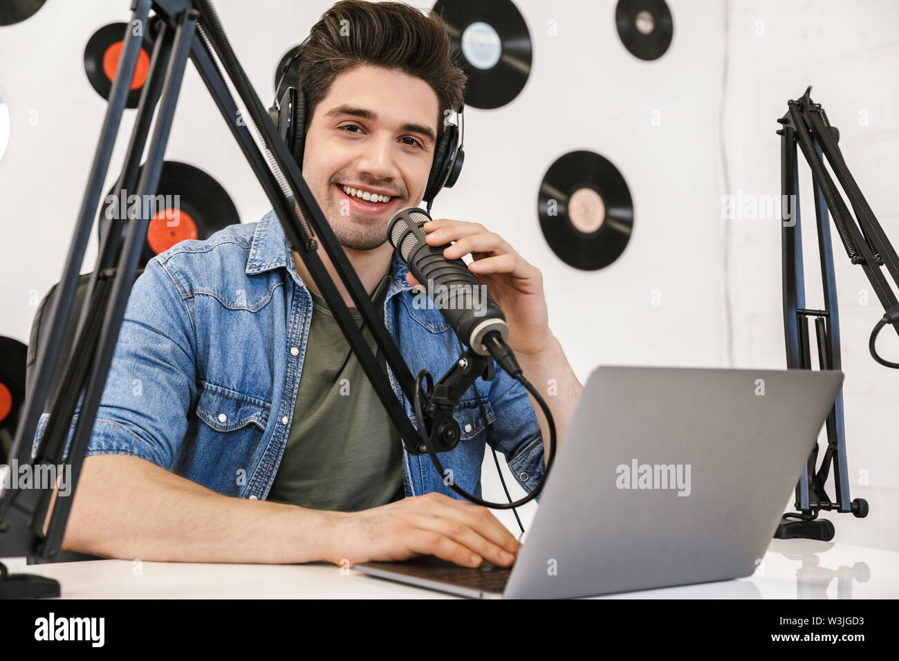 Happy young man radio host broadcasting through microphone in studio ...