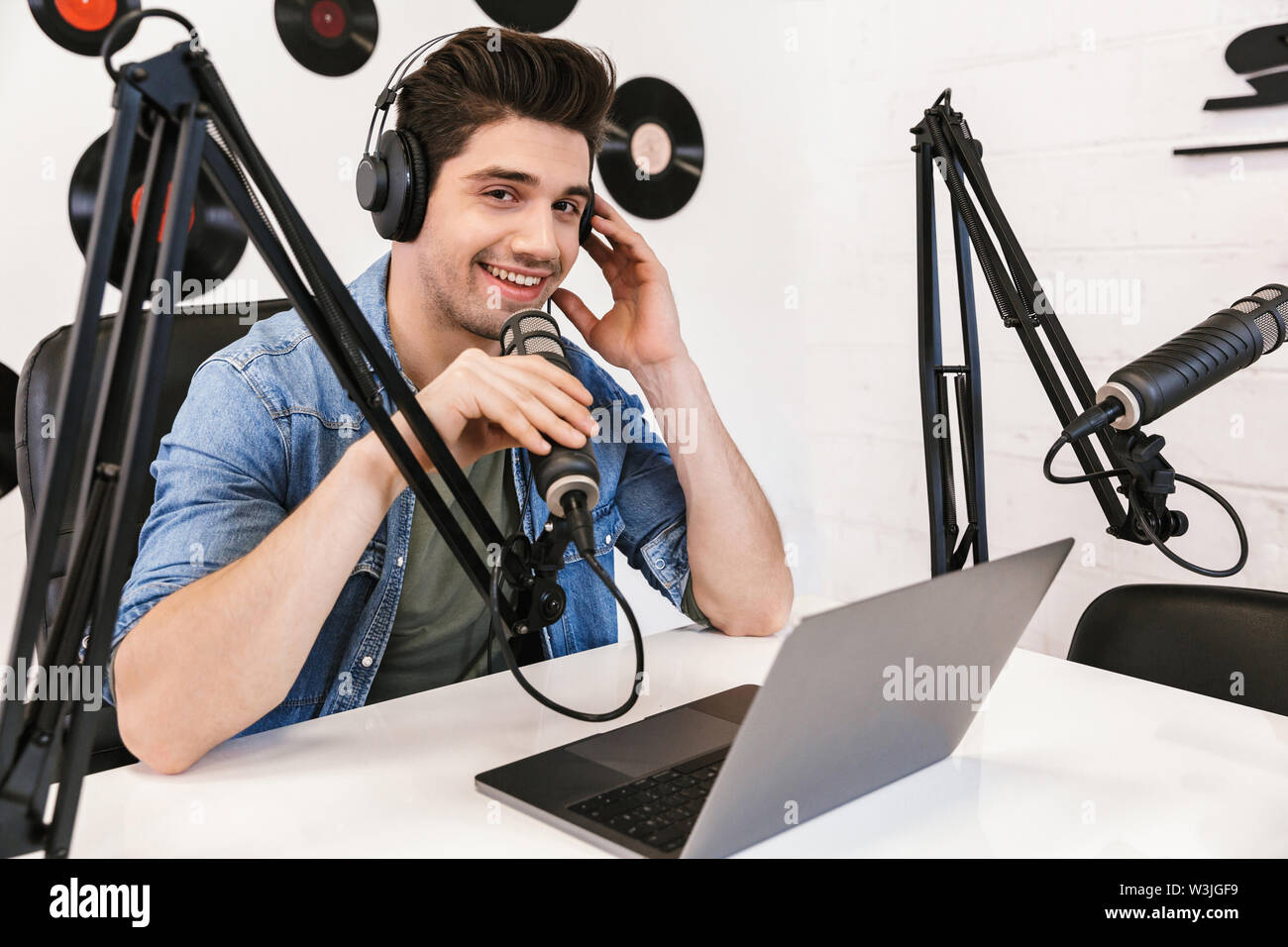 Happy young man radio host broadcasting through microphone in studio ...