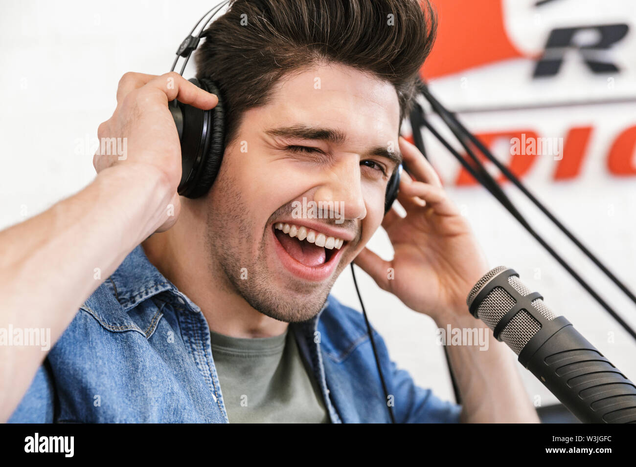 Handsome happy young male radio host broadcasting in studio, using ...