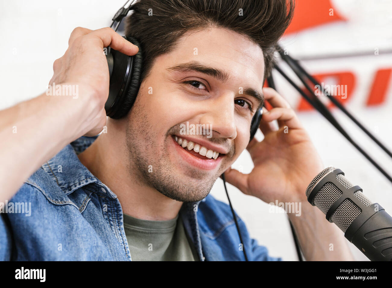 Handsome happy young male radio host broadcasting in studio, using ...