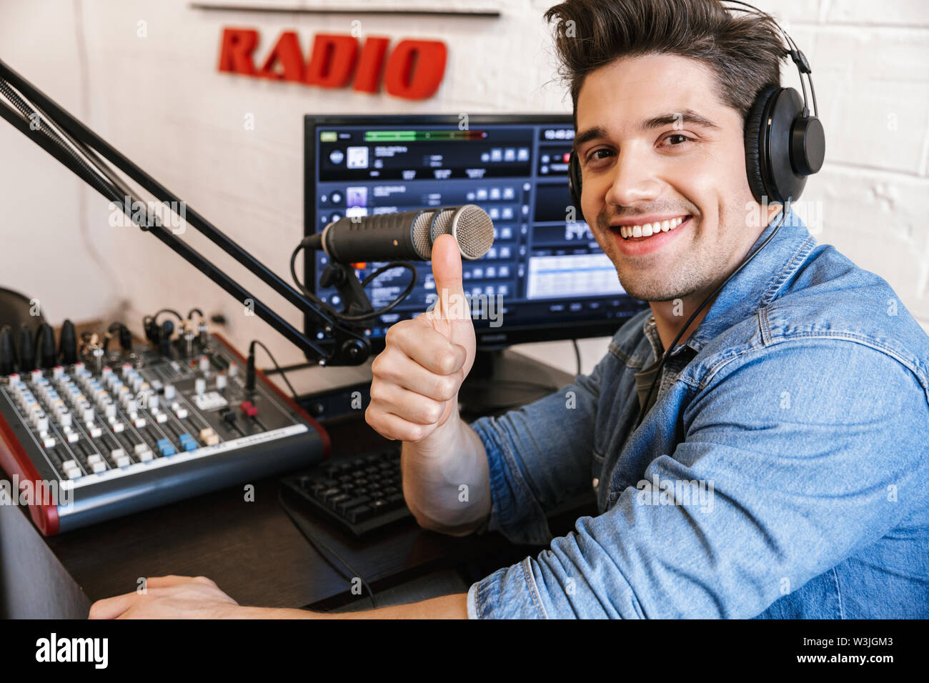 Handsome happy young male radio host broadcasting in studio, using ...