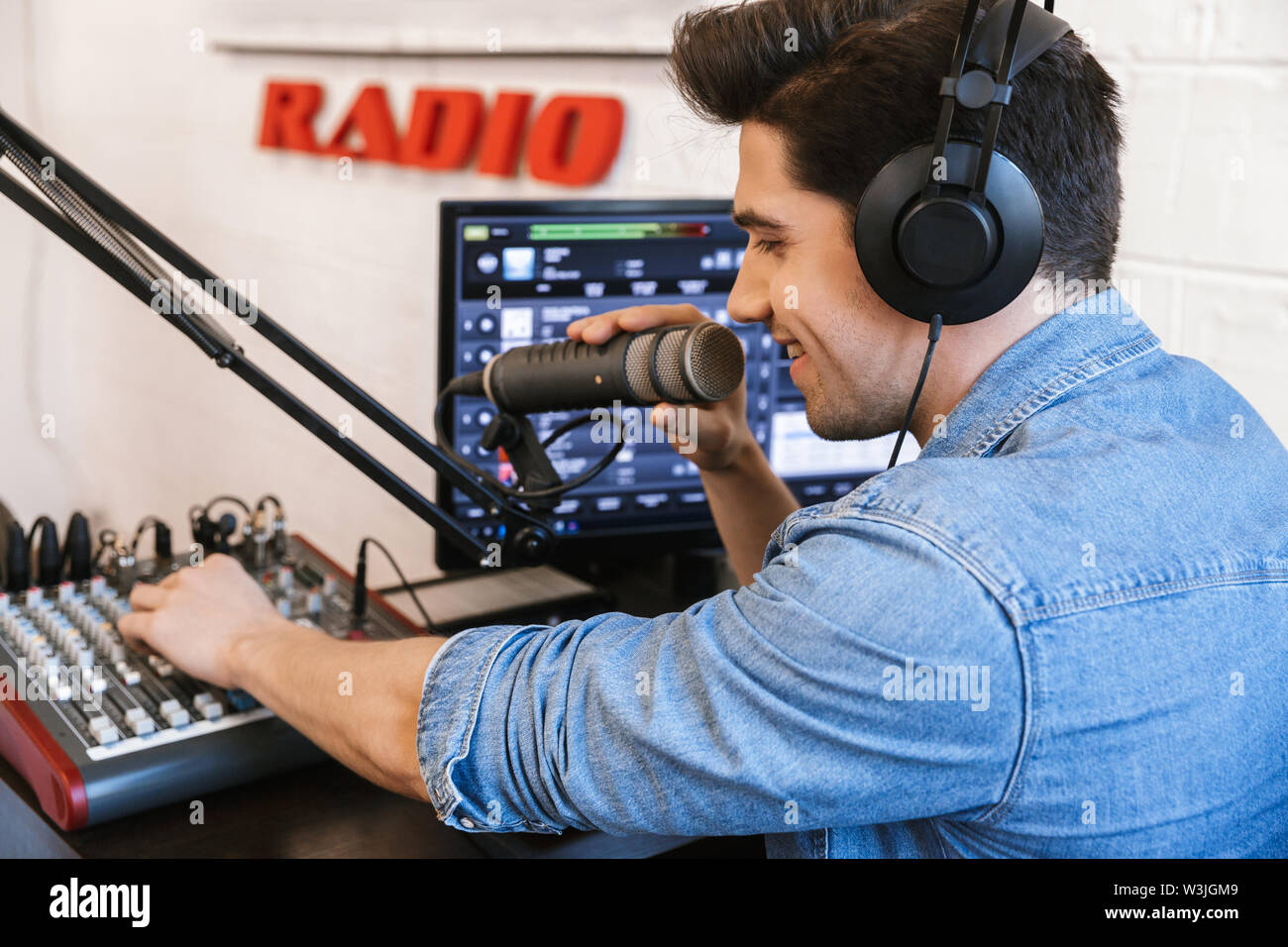 Handsome happy young male radio host broadcasting in studio, using ...