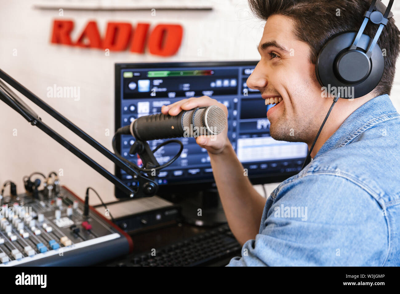 Handsome happy young male radio host broadcasting in studio, using ...