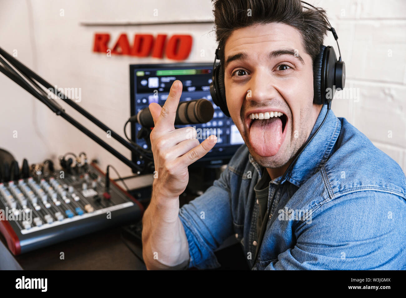 Image of a handsome young man radio host at the workspace with ...