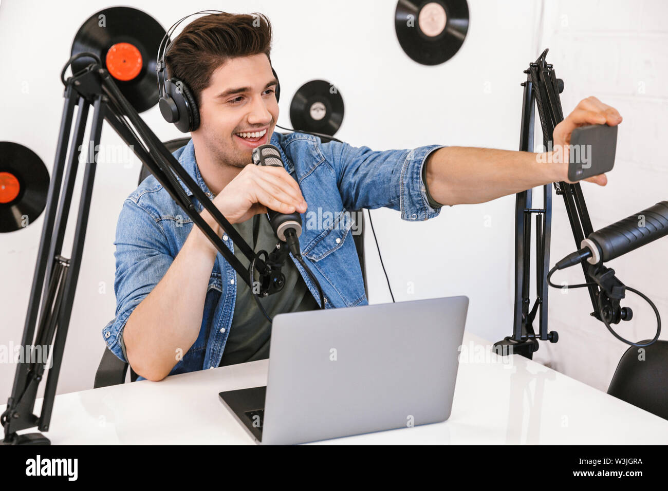 Handsome happy young male radio host broadcasting in studio, using ...