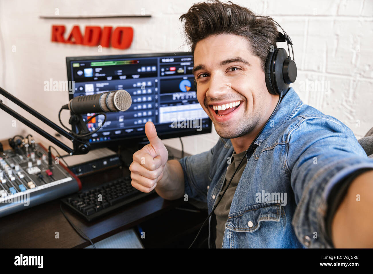 Handsome happy young male radio host broadcasting in studio, using ...