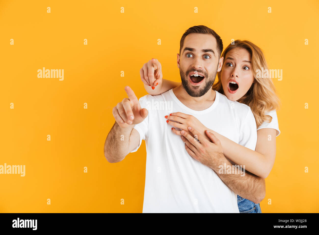 Image of shocked couple man and woman expressing wonder while pointing ...