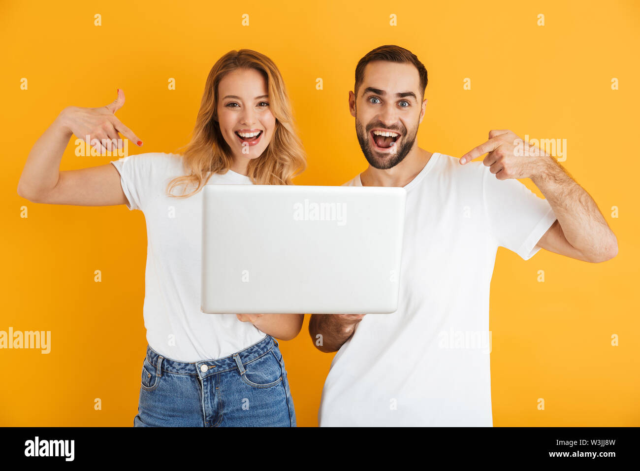 Image of excited couple man and woman rejoicing together while pointing ...