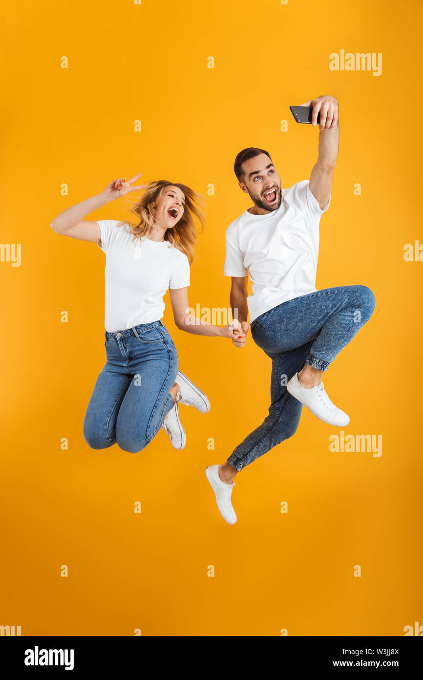 Full length image of funny couple rejoicing and jumping while taking ...