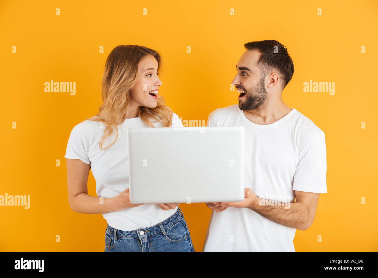Image of pretty couple man and woman rejoicing while holding laptop ...
