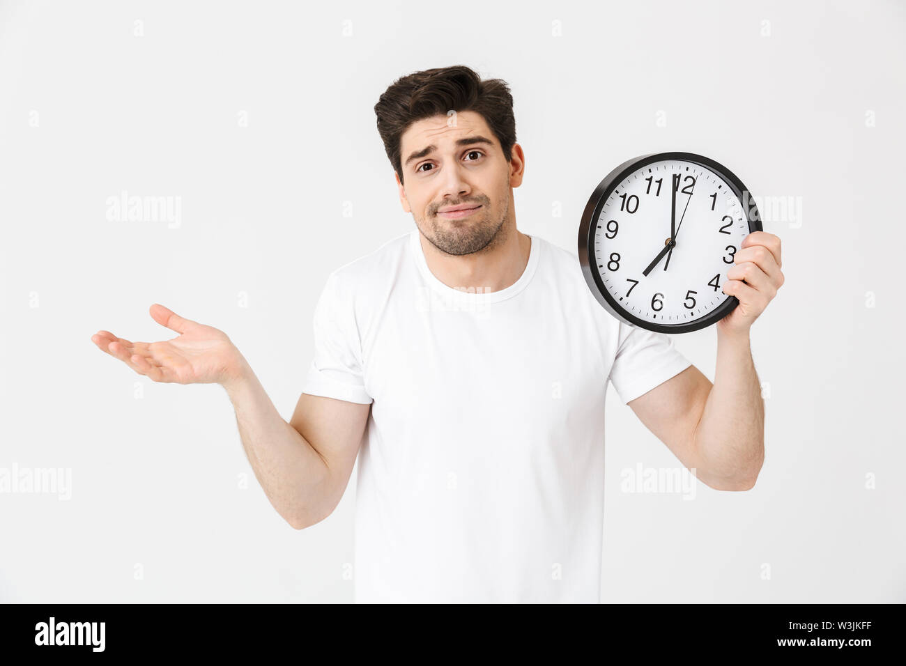 Image of confused young man posing isolated over white wall background ...