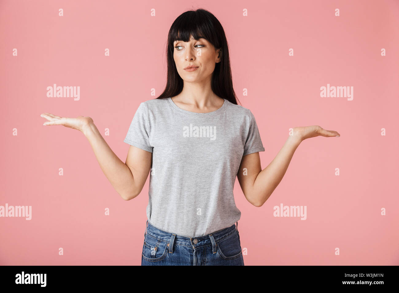 Image of a beautiful confused woman posing isolated over light pink ...