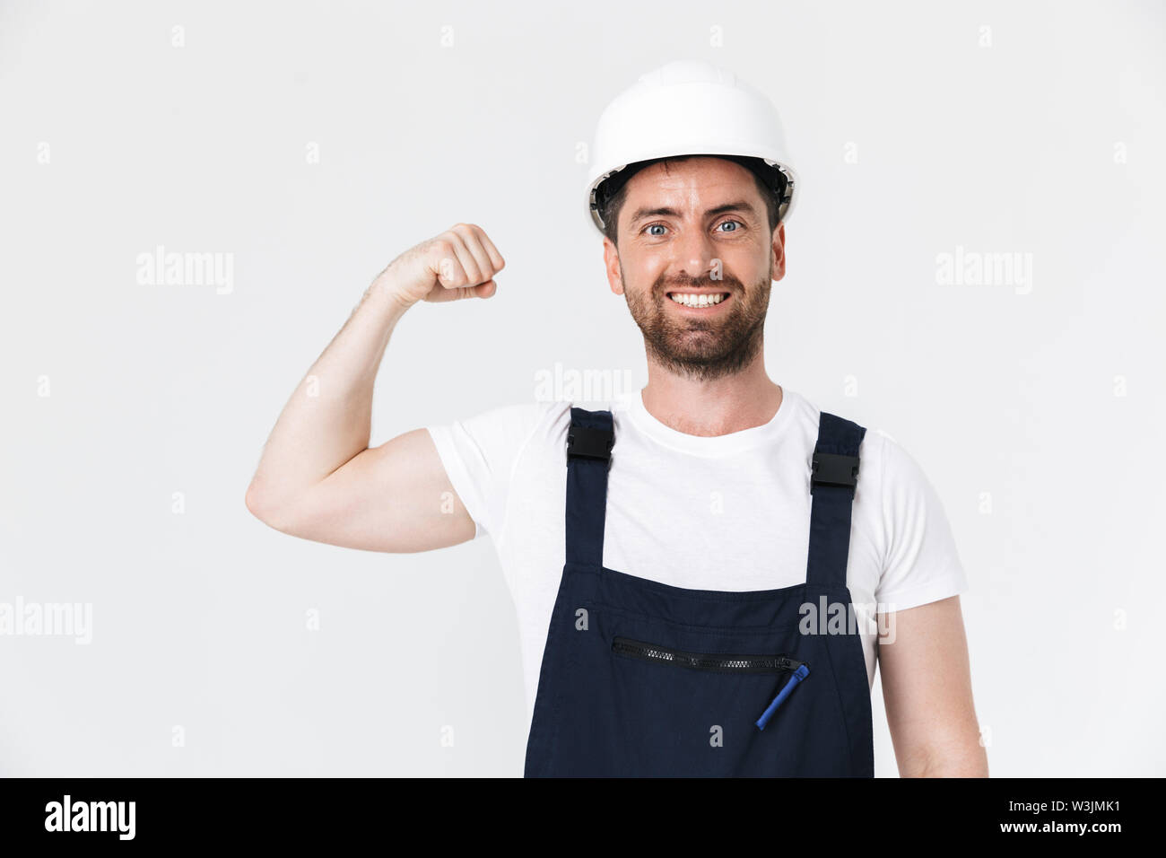 Confident bearded builder man wearing overalls and hardhat standing ...