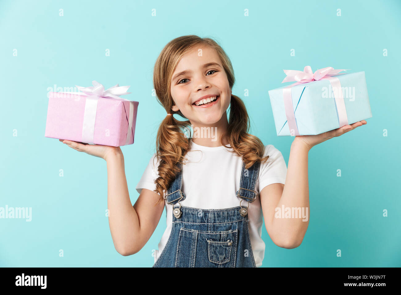 Portrait of a cheerful little girl isolated over blue background ...