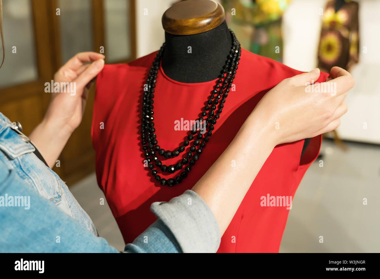Female designer working with new model tailoring dress on mannequin in ...