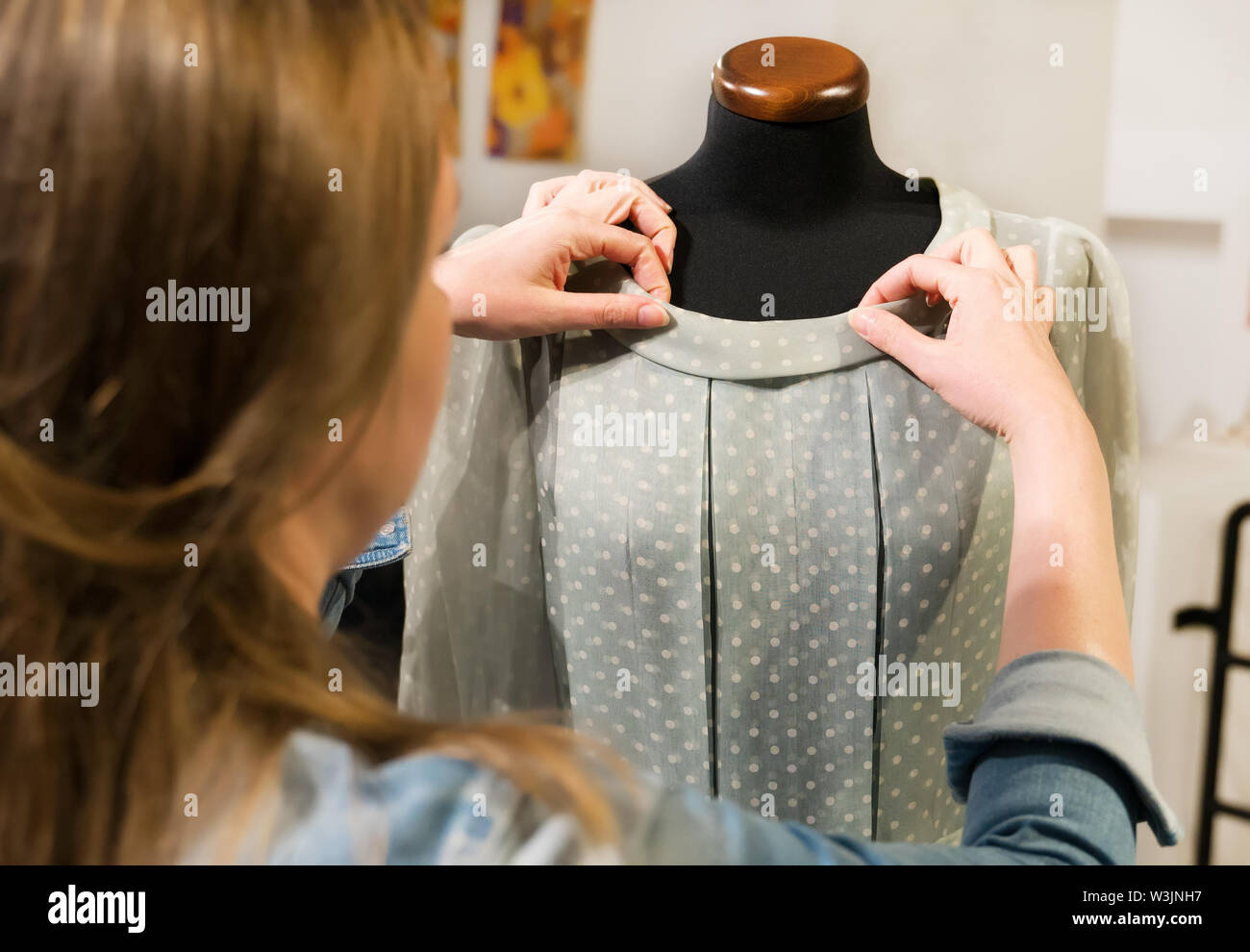Female designer working with new model tailoring dress on mannequin in ...