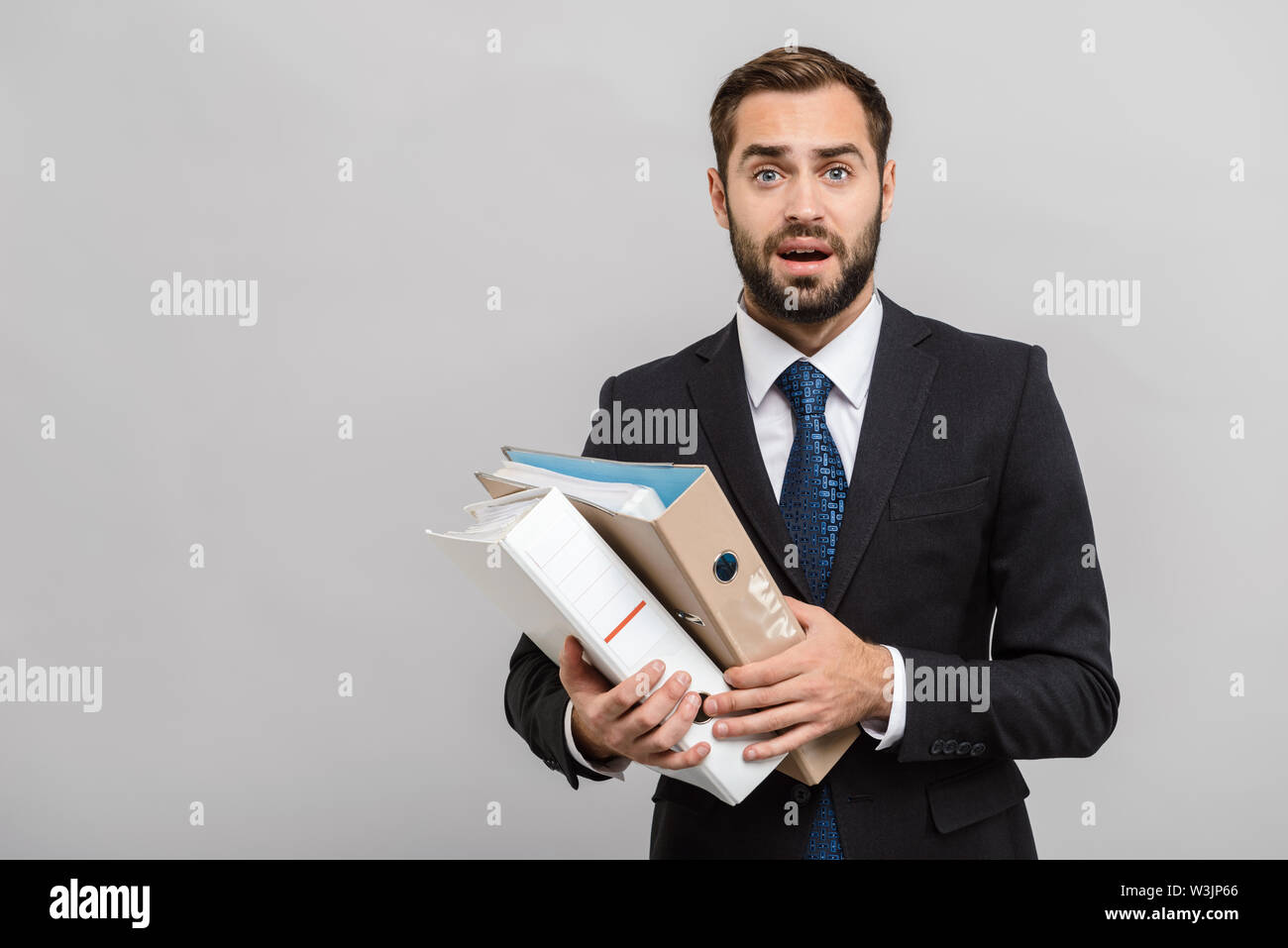 Attractive busy young businessman wearing suit standing isolated over ...