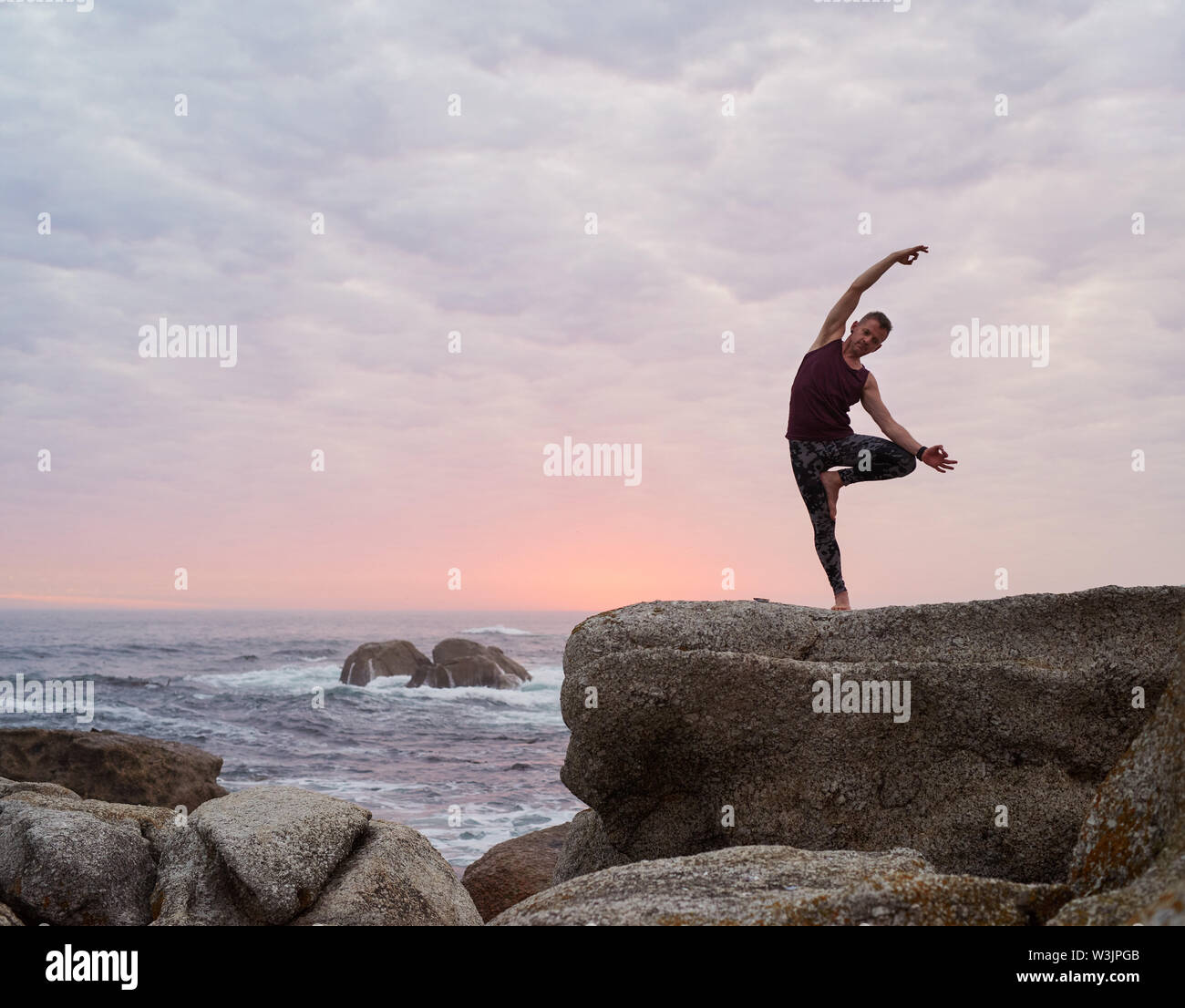 Man doing the tree pose by the ocean at dusk Stock Photo - Alamy