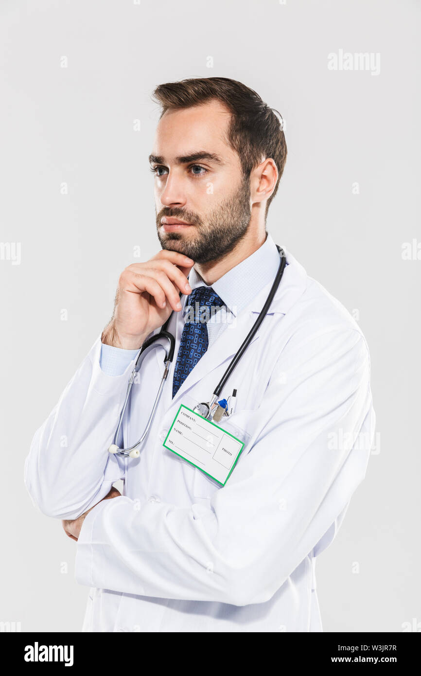 Portrait of serious young medical doctor with stethoscope looking aside ...