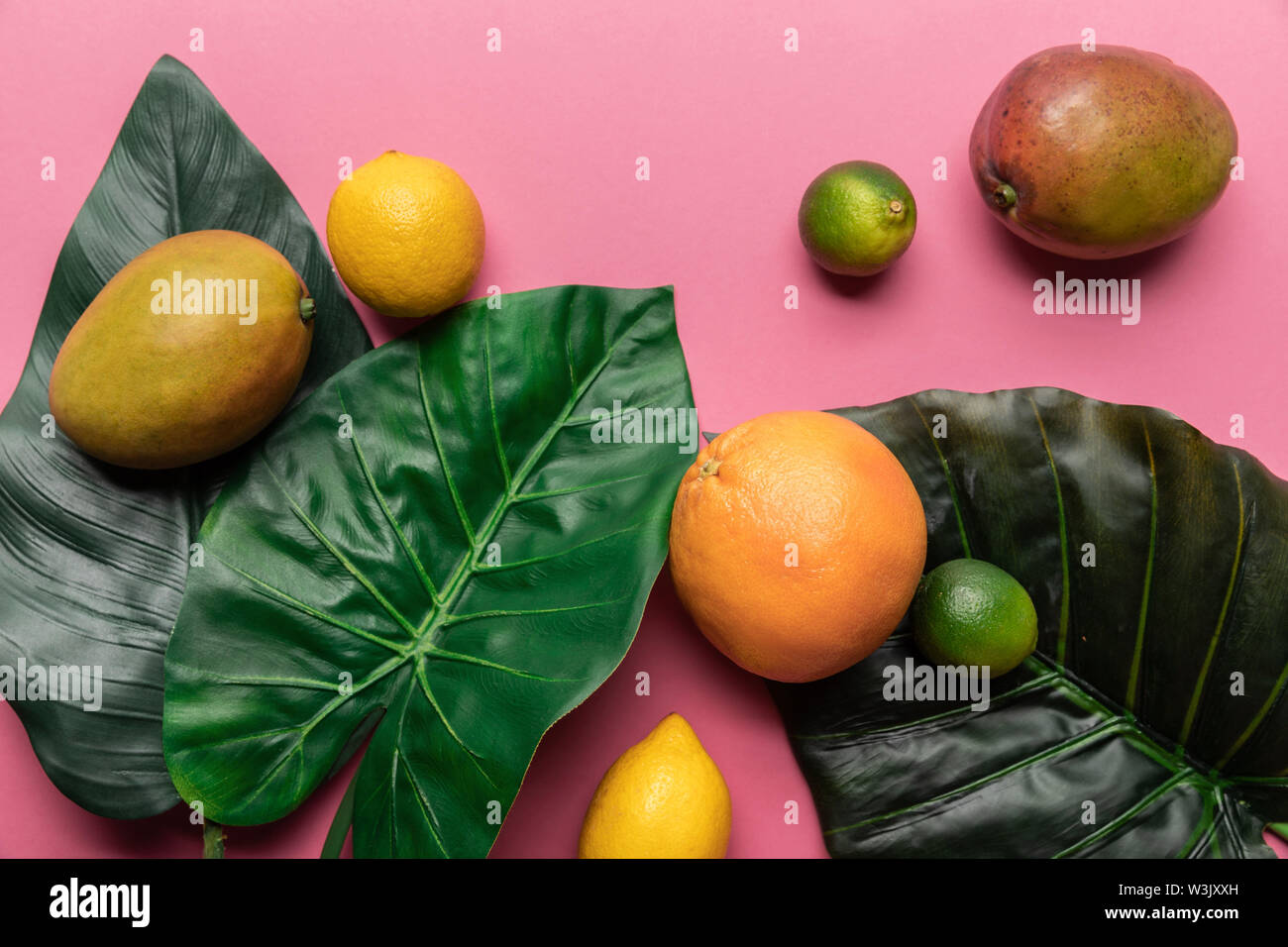 top view of whole ripe tropical citrus fruits and mango with green ...