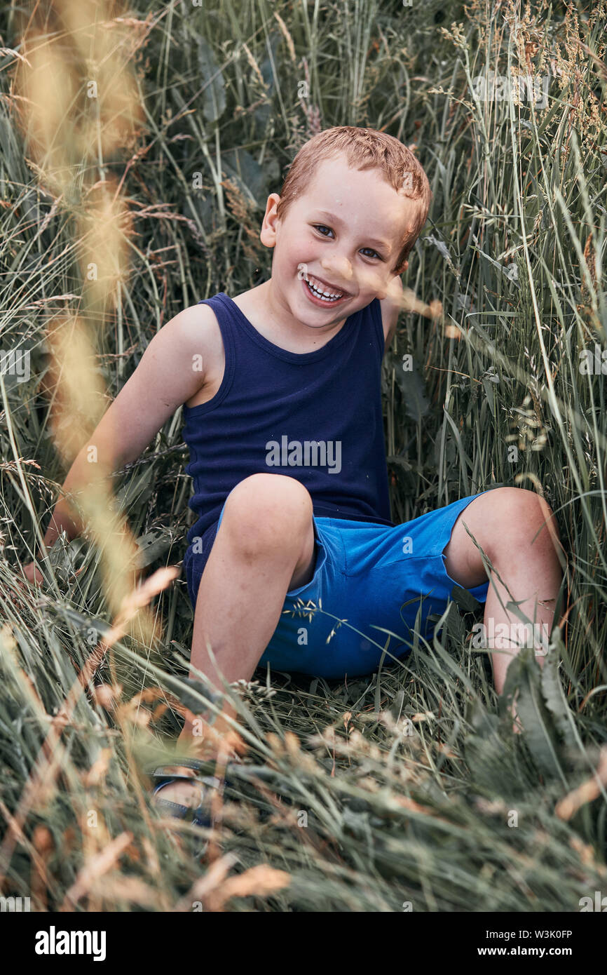 Little happy smiling kids playing in a tall grass in the countryside ...