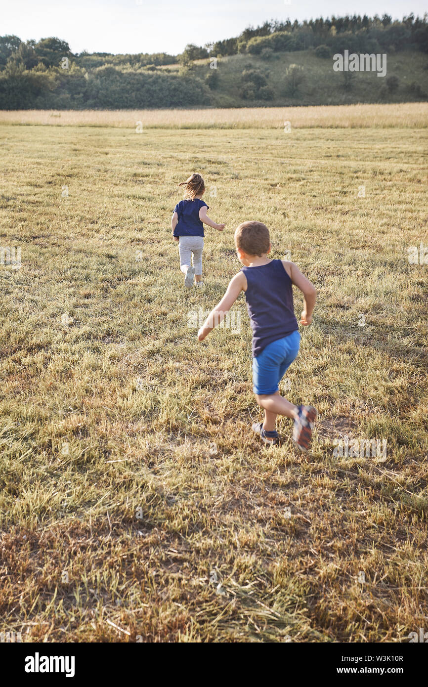 Children running through a field. Little girl and boy playing in the ...